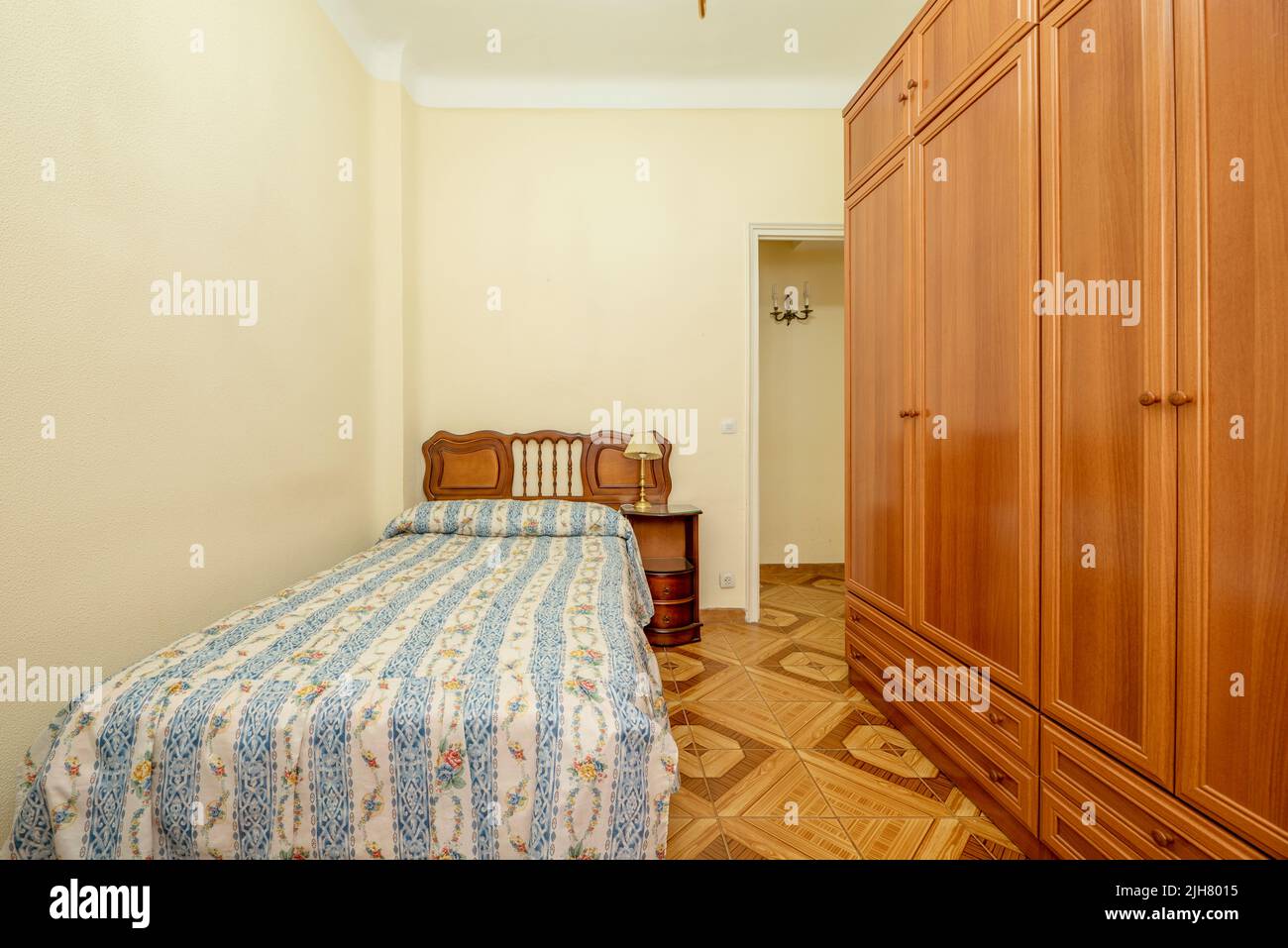 Room with a wall covered by a large six-door wooden wardrobe, a red ...