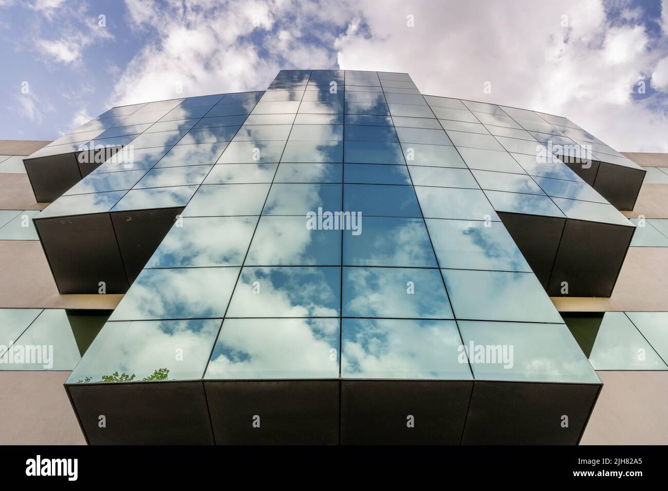 Office building facade with lots of mirrors reflecting the sky and ...