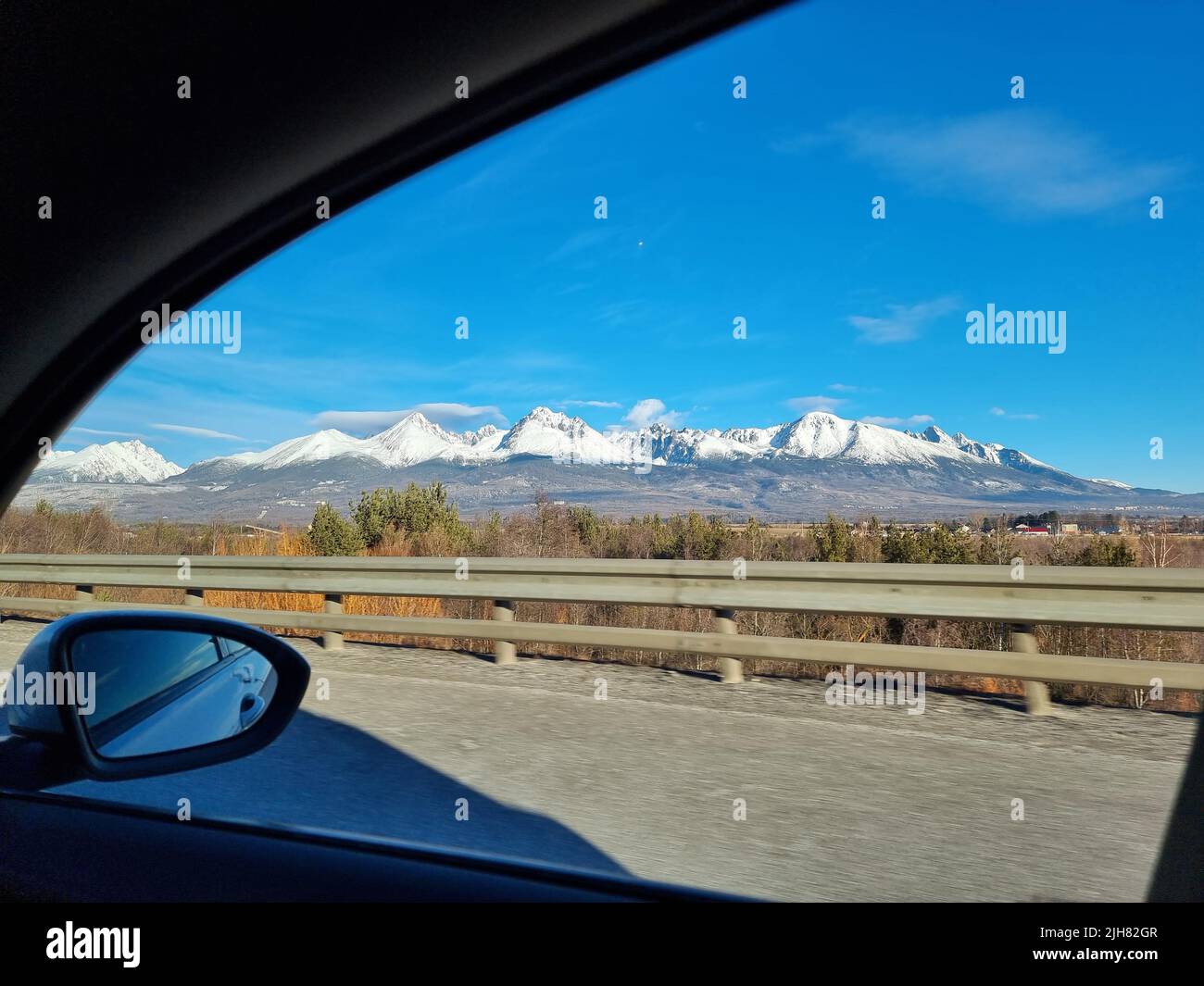 side view from the window of a car on a road with high tatras mountains ...
