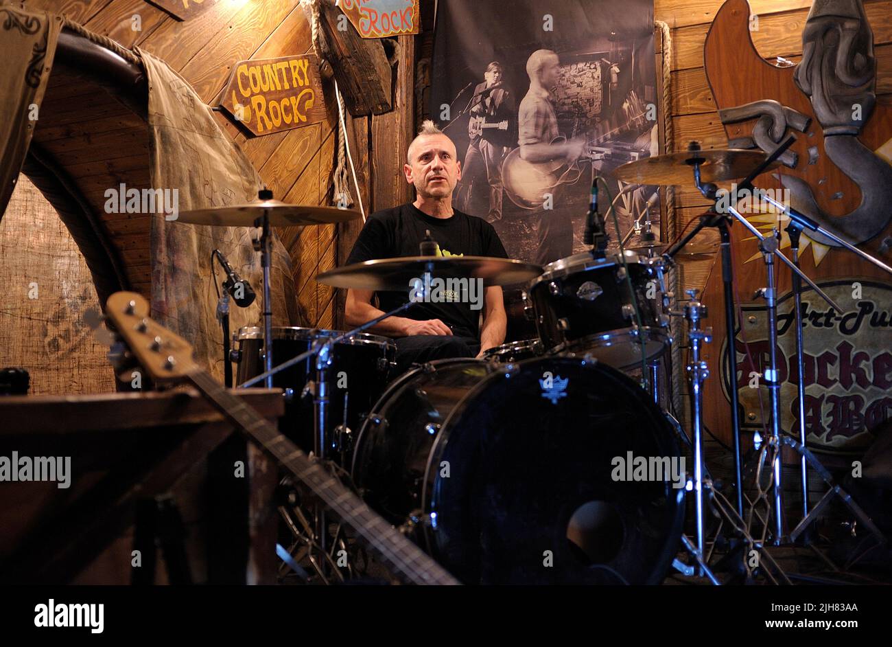 Old man drummer playing drums on stage at the small art cafe. December ...