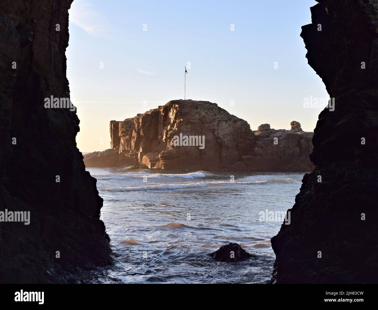Chapel Rock on Perranporth beach at sunset from cave entrance Stock ...
