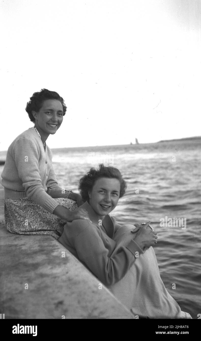 1940s, historical, two young ladies, sitting together on a harbour or ...