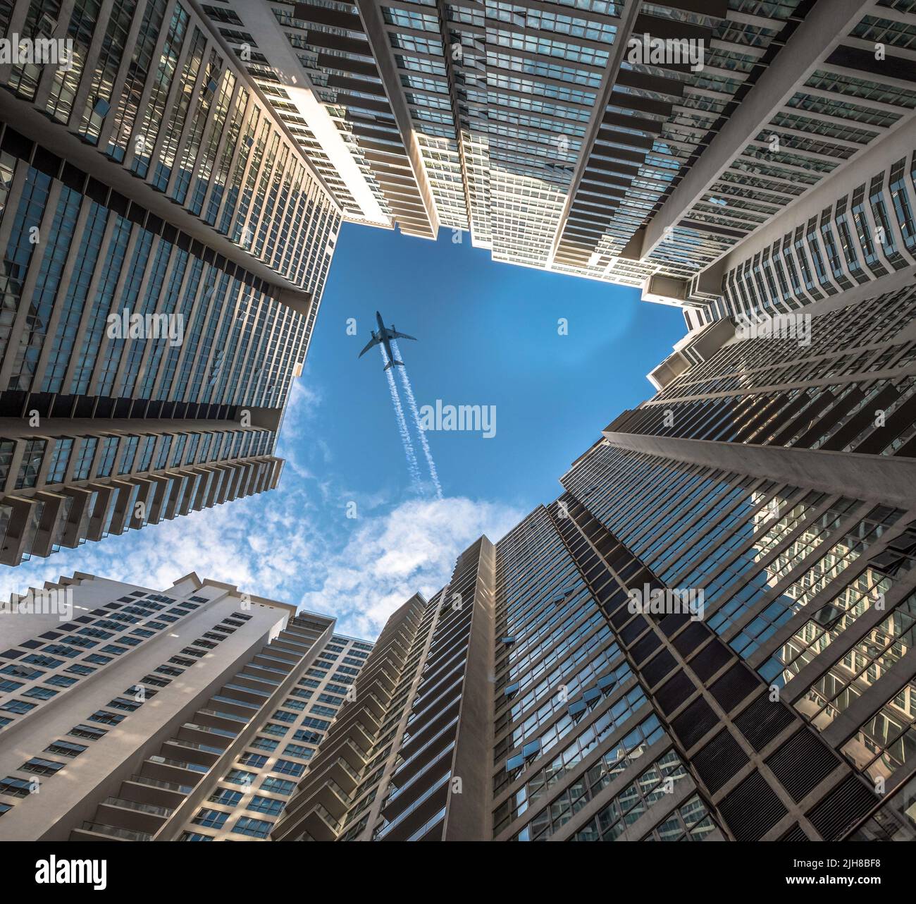 A bottom view from the buildings of a plane in the blue sky Stock Photo ...