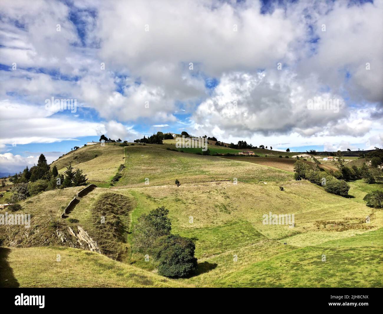 A scenic view of a hill behind the fields on a cloudy day Stock Photo ...