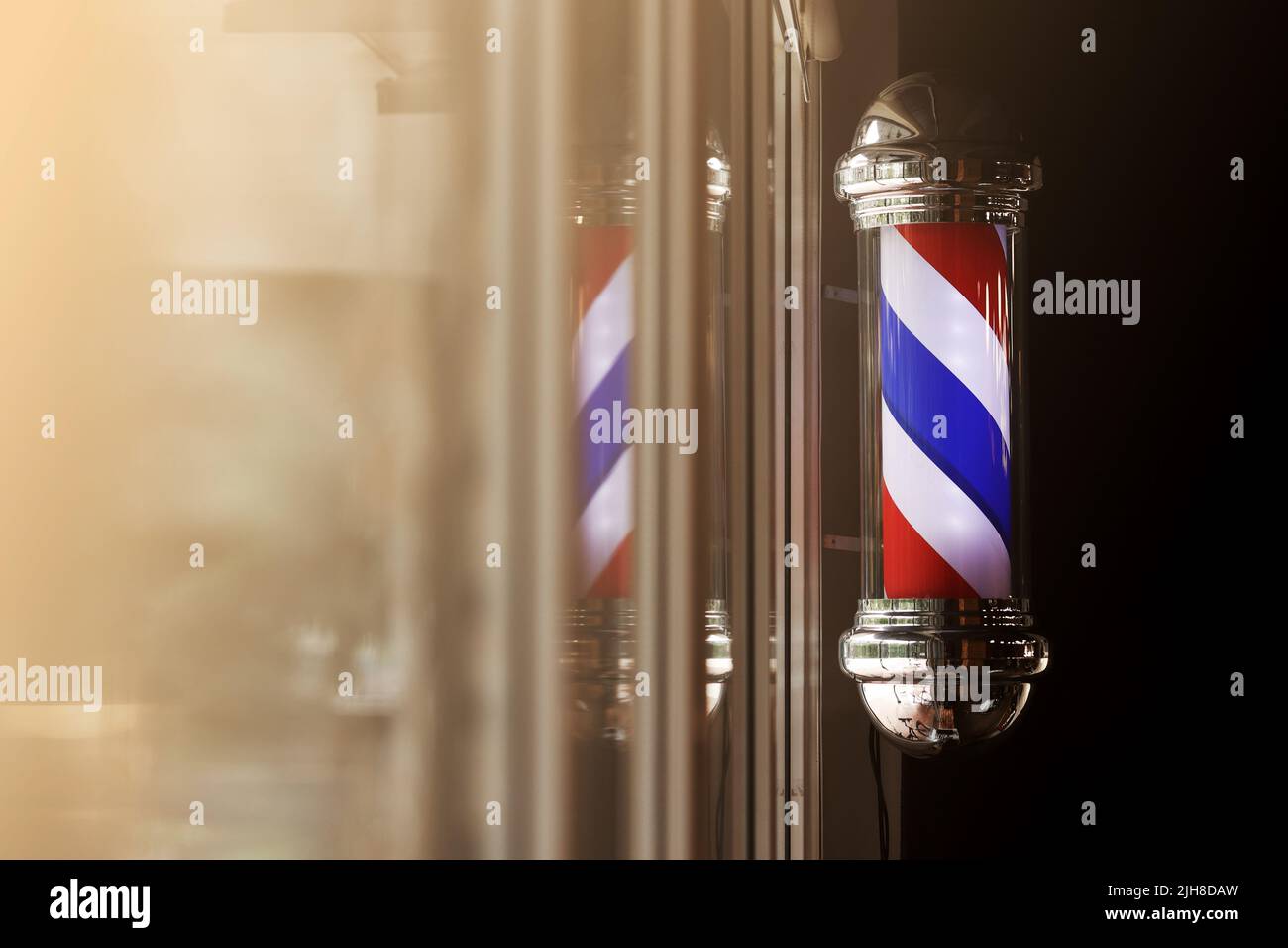Barber pole spinning at night. International barbershop pole sign. A ...