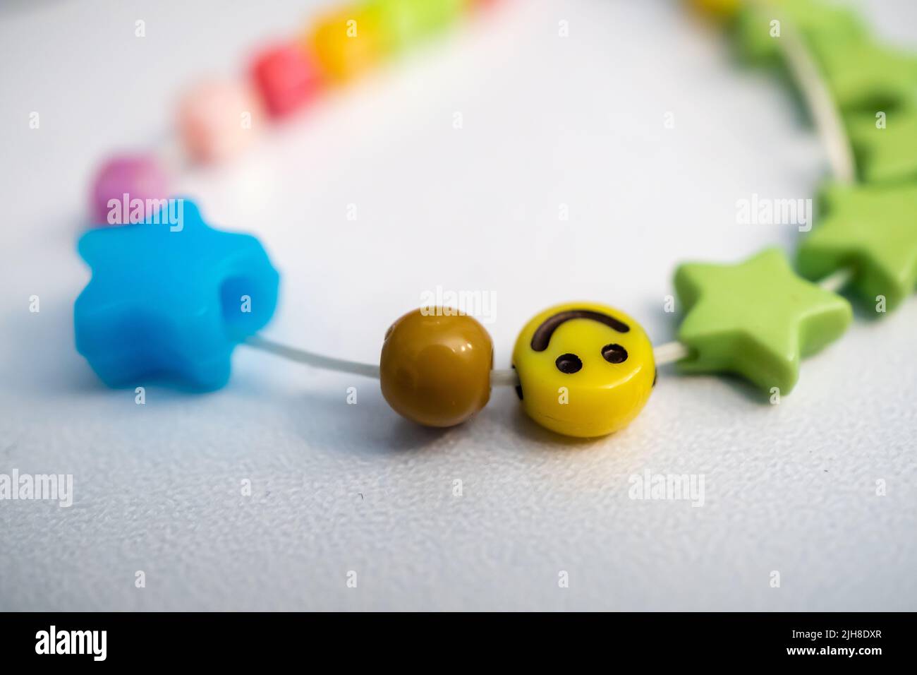A closeup shot of a beaded bracelet with stars and a yellow smiley face ...