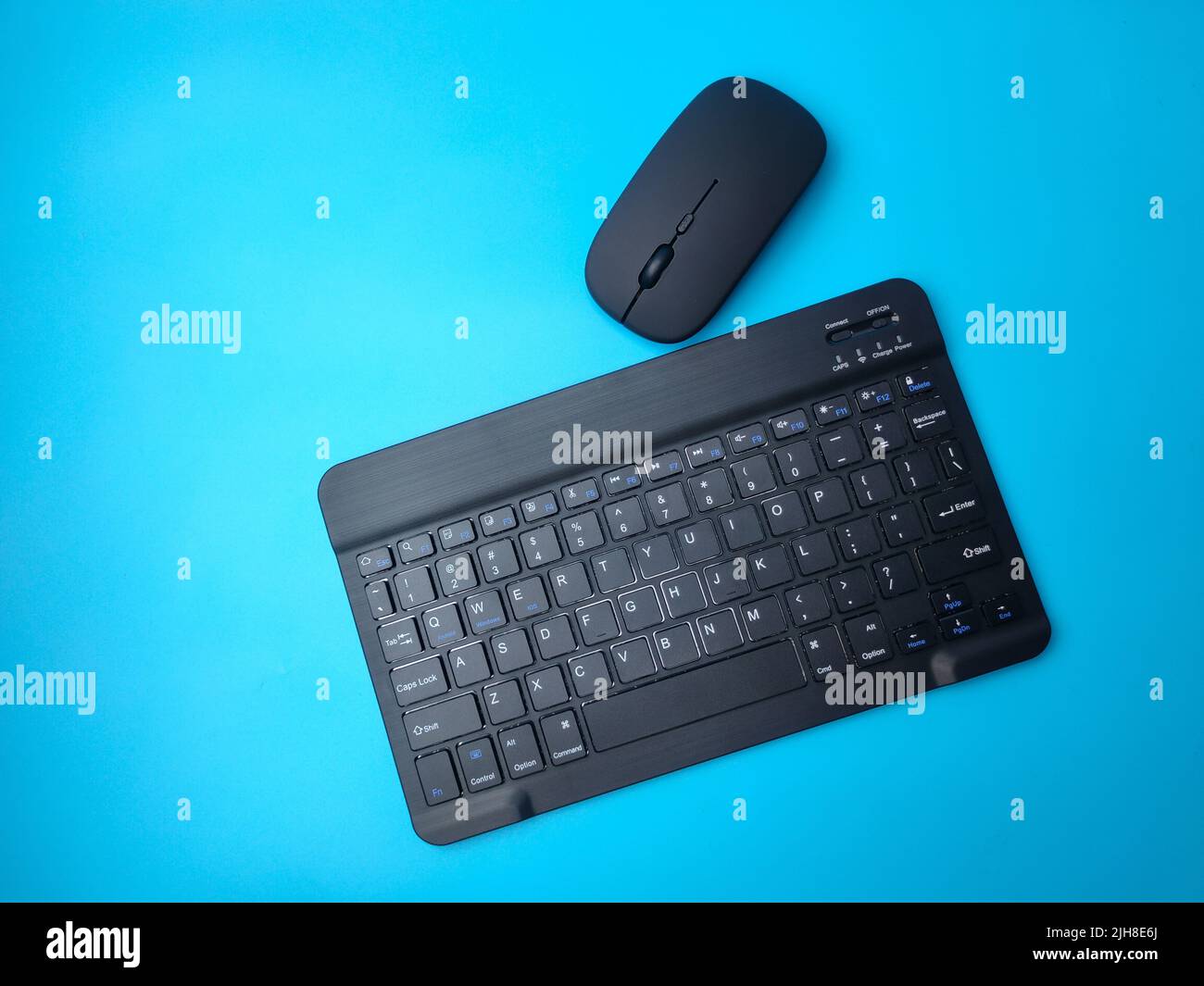 A black Bluetooth wireless keyboard and wireless mouse on a blue ...