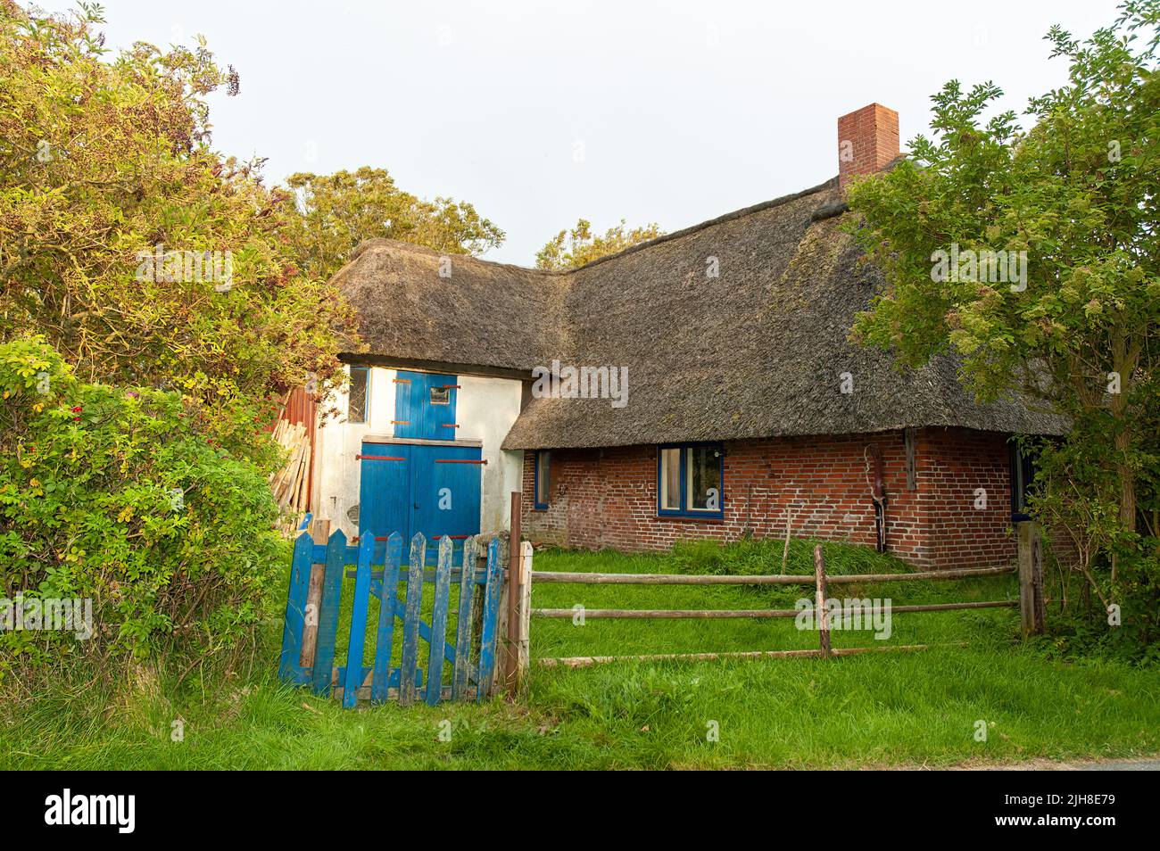 A small run-down brick house with blue fences and doors in Westerhever ...
