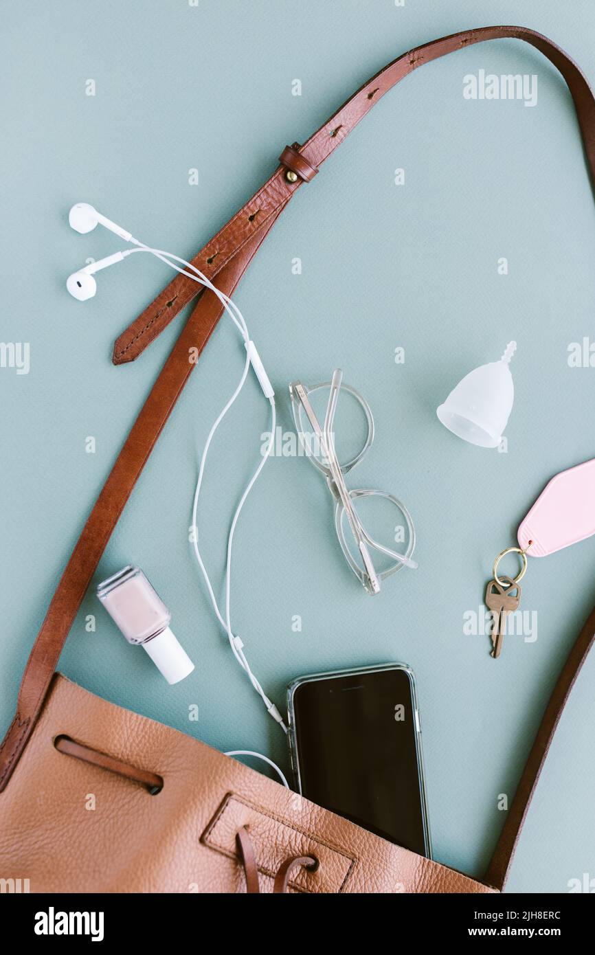 The vertical of the contents of woman's purse spilling against the gray ...