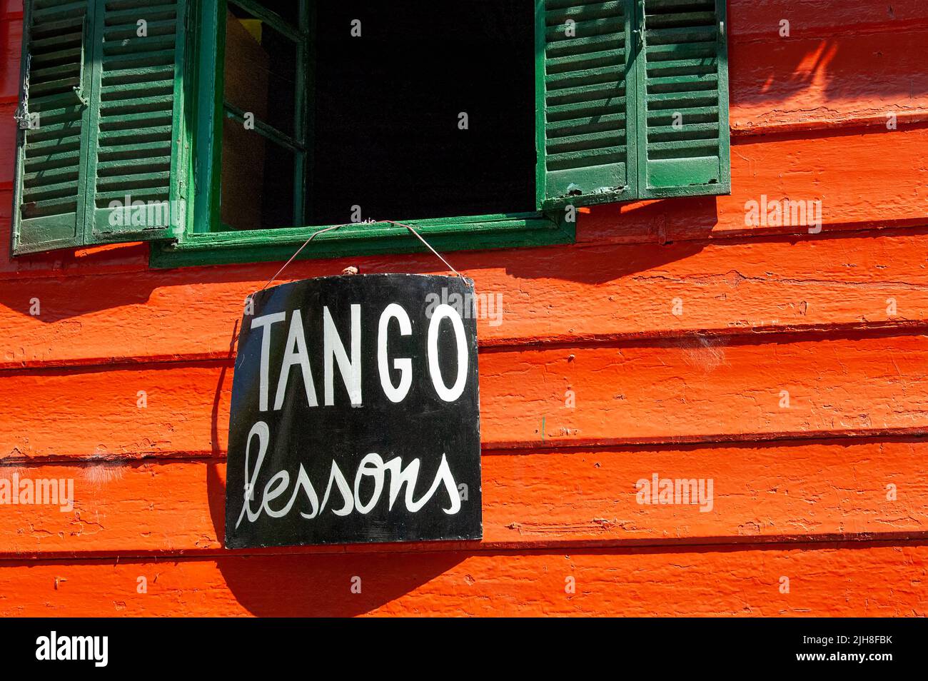 The "TANGO lessons" sign hanging from an old wooden window with green ...