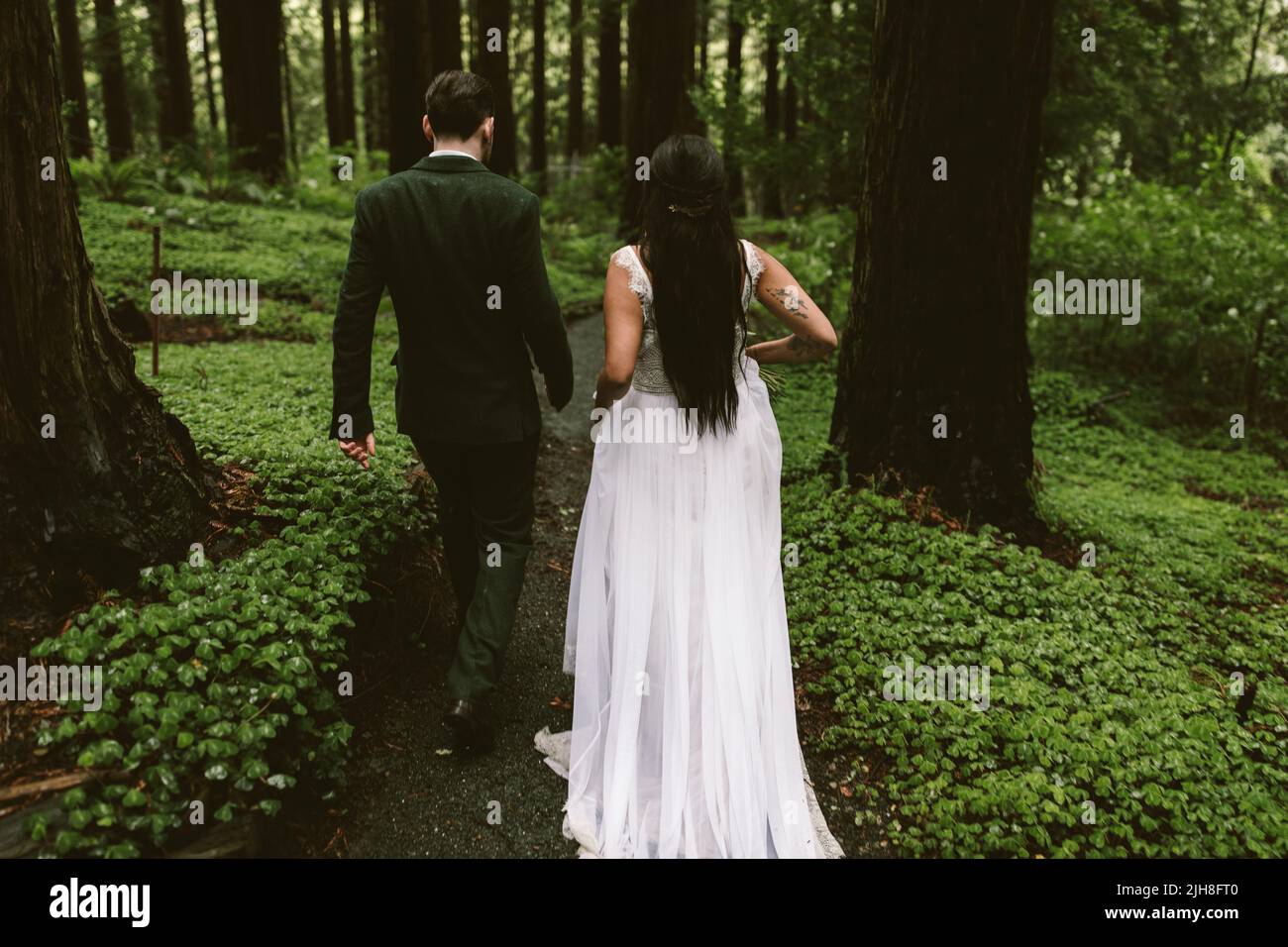 The bride and groom holding walking through the garden Stock Photo - Alamy