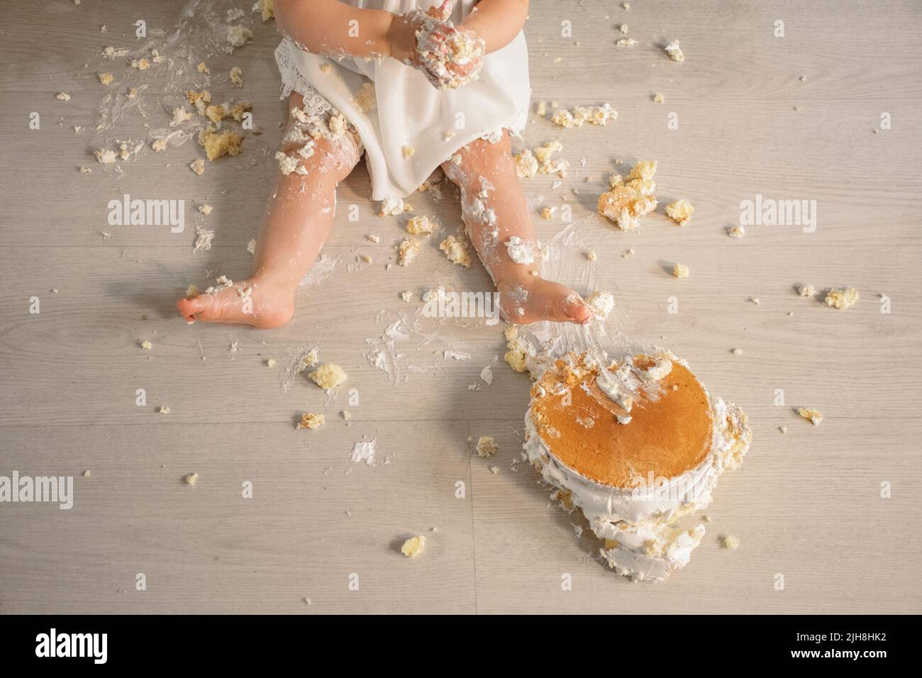 Legs of a one-year-old child are shown covered with pieces of cake. We ...