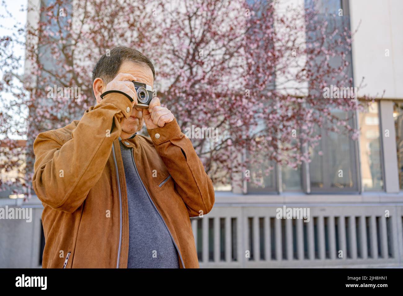A closeup of older man enjoying his old film camera photographing the ...