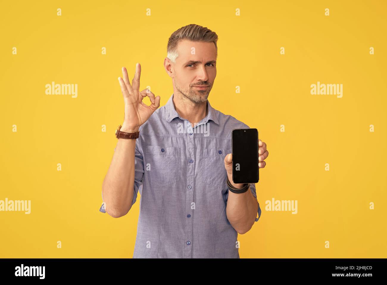 man hold phone and show ok gesture on yellow background, copy space ...
