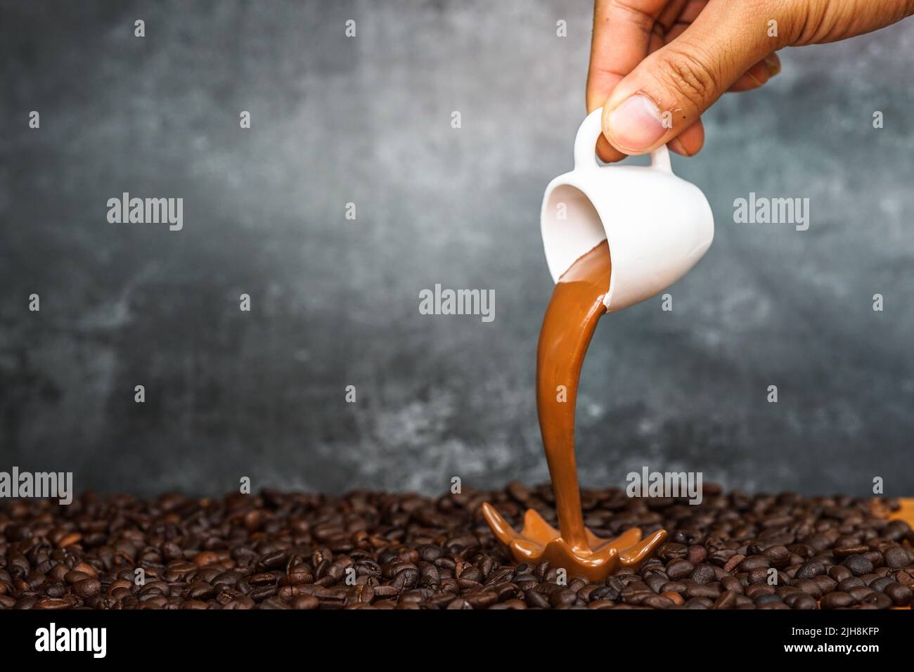 A man spilling espresso on coffee beans from a miniature cup Stock ...