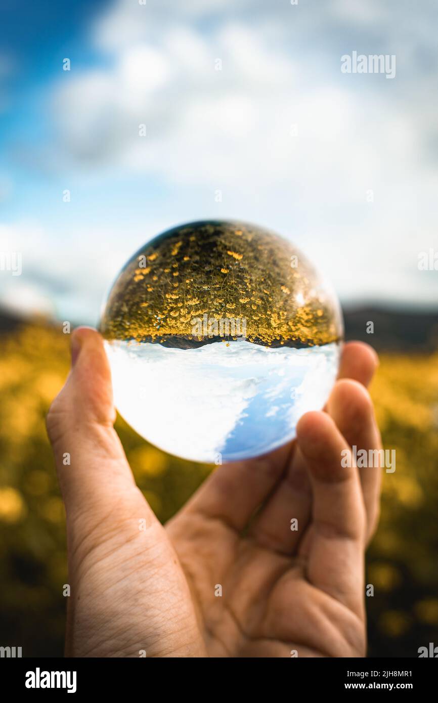 A vertical shot hand holding a crystal glass ball with a flipped ...
