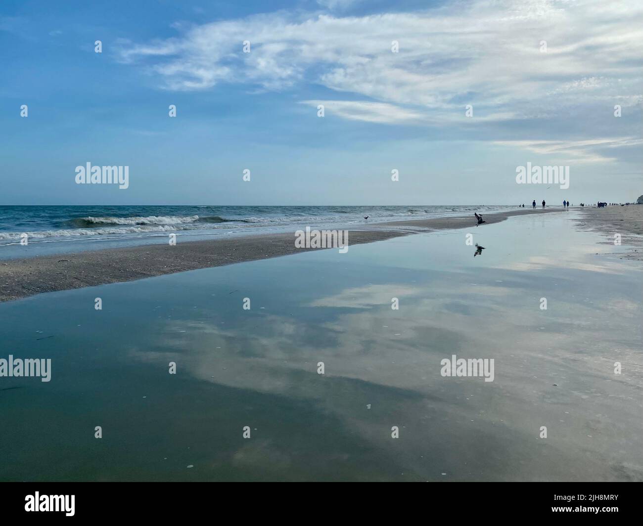 A soft tide on a beach with he sky reflecting in the shallow waters ...