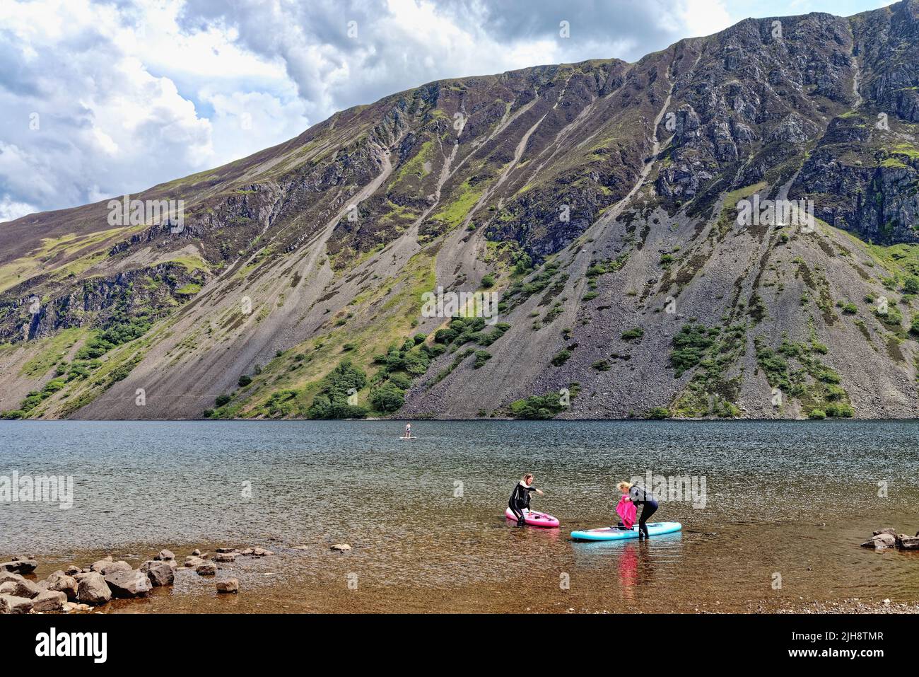 Paddleboarders on Wastwater lake with the dramatic scree slopes in the ...