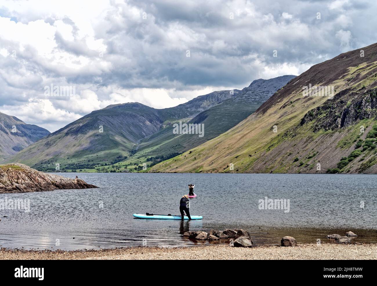Paddleboarders on Wastwater lake with the dramatic scree slopes in the ...