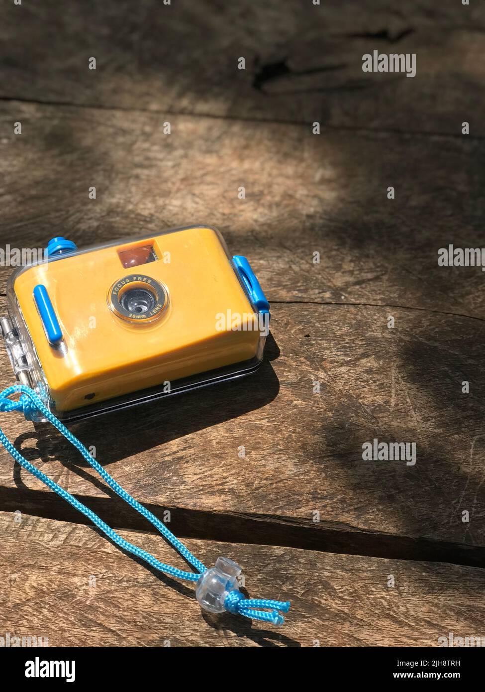 A vertical shot of a small yellow camera with a blue string in a clear ...