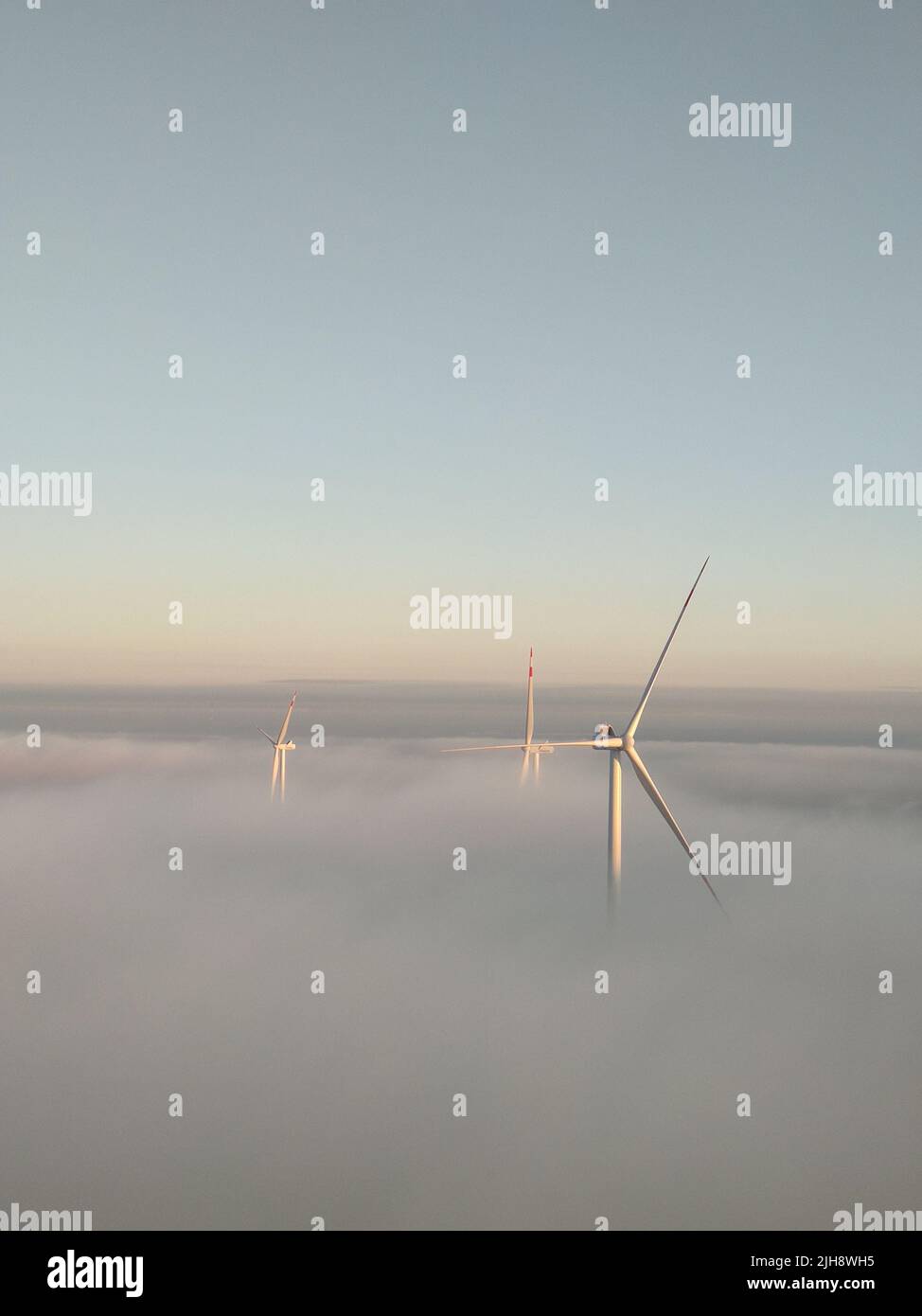A view of a windmill farm in the clouds at sunrise Stock Photo - Alamy