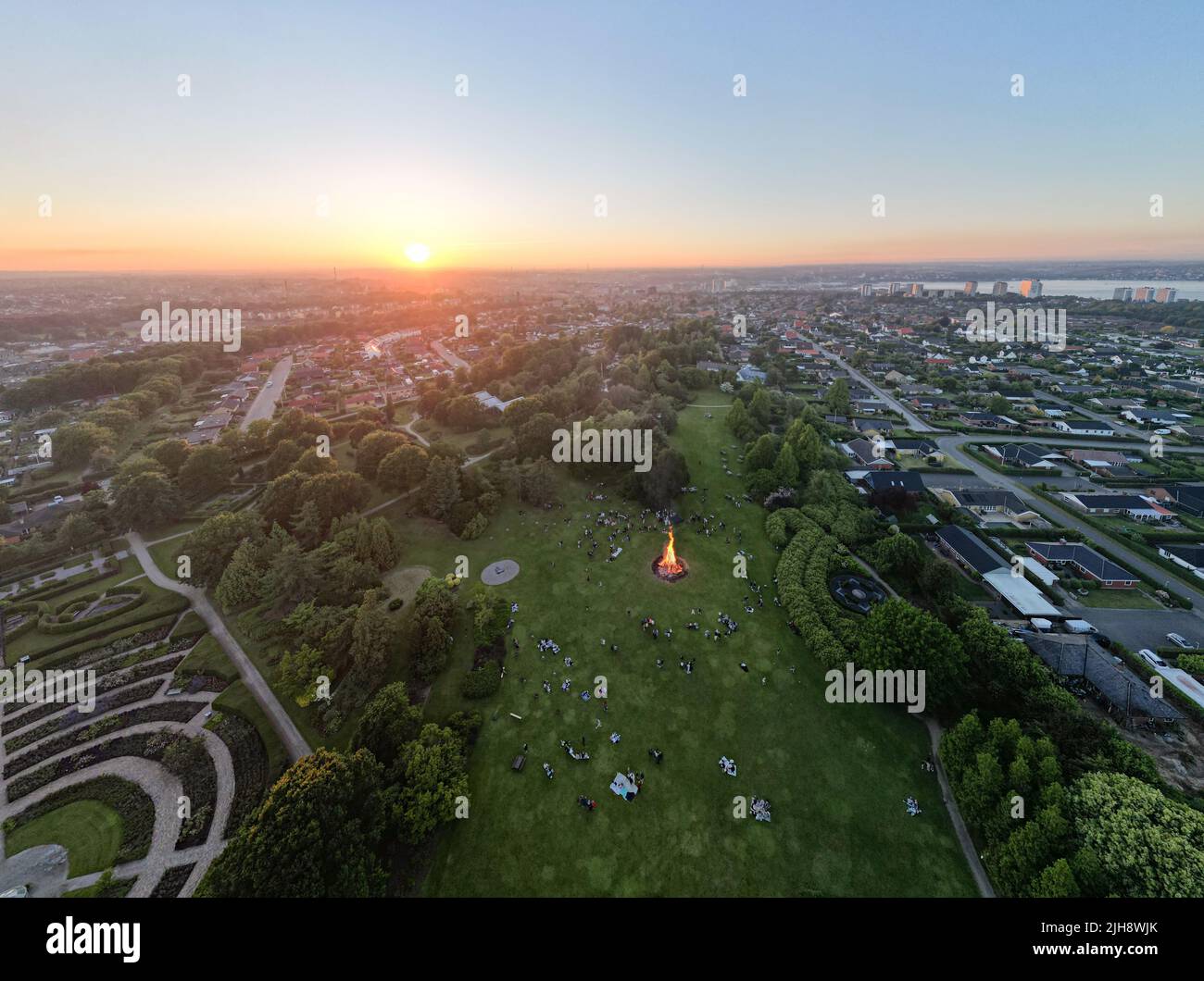 An aerial view of lush green urban park with bonfire in the center ...