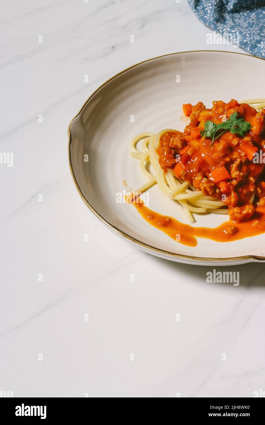 A vertical shot of spaghetti bolognese on a white marble table with a ...