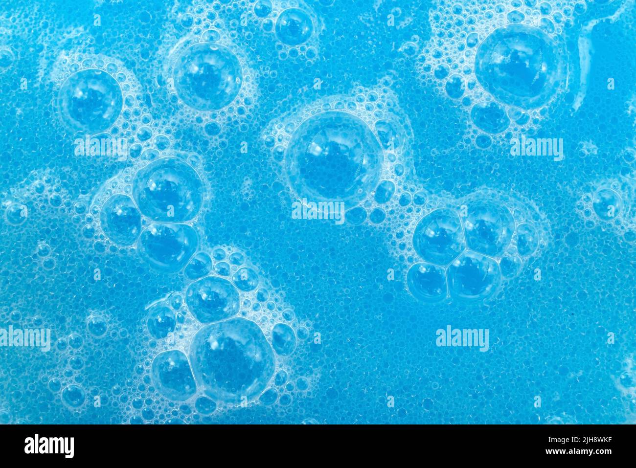 Soap foam in blue close-up. Foam bubbles on the surface of detergent or ...