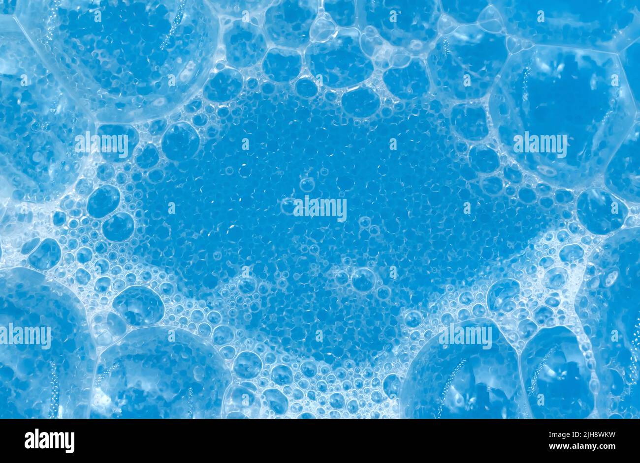 Soap foam in blue close-up. Foam bubbles on the surface of detergent or ...