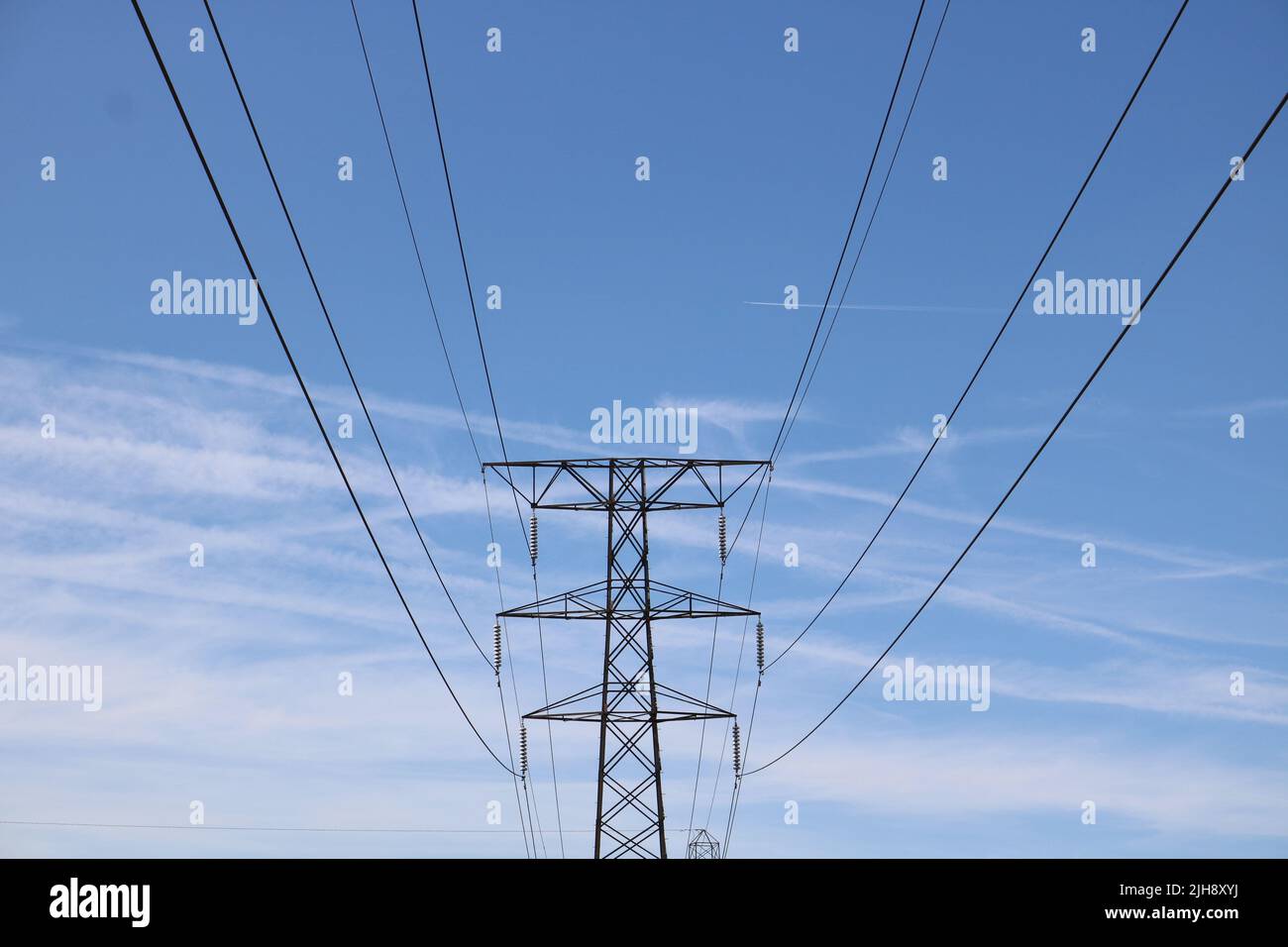 Electricity pylon against blue wispy cloudy sky with space for copy ...