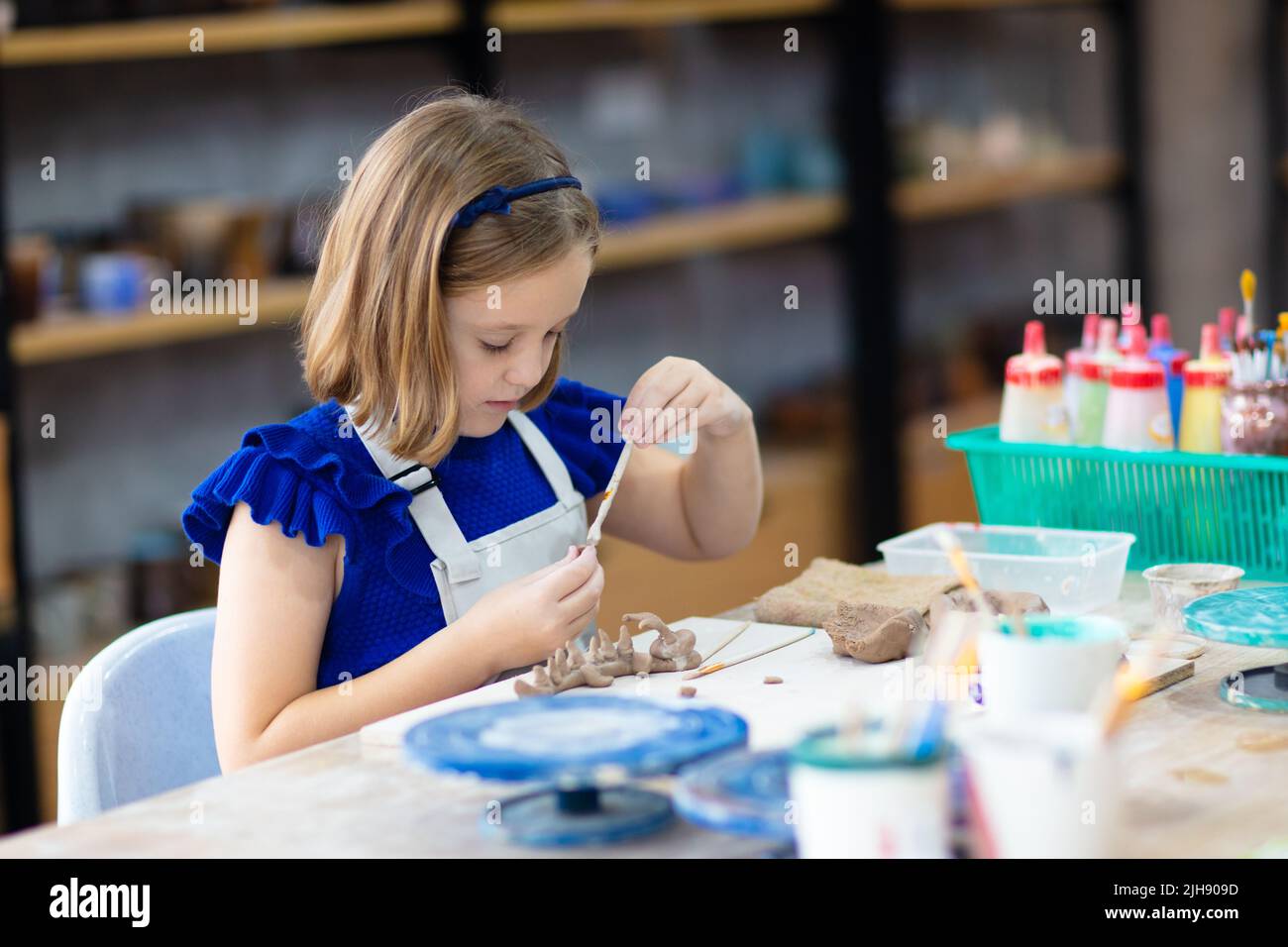 Child working on pottery wheel. Kids arts and crafts class in workshop ...