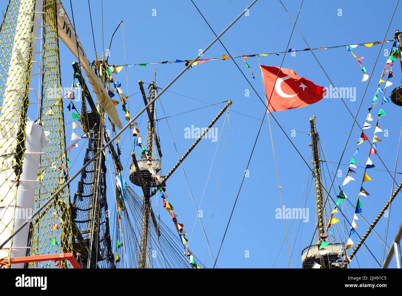 A Turkish flag on a ship among the sailing masts, blue sky background ...
