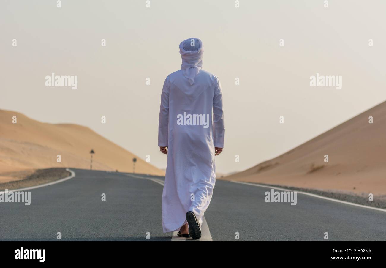 Emarati Arab man walking on the road in the desert, Dubai, United Arab ...
