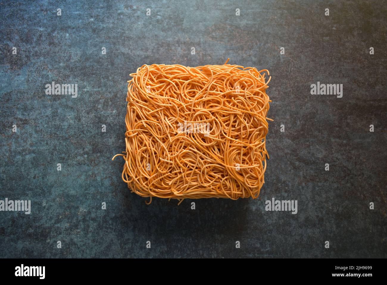 Raw whole dried orange color square noodles block Stock Photo - Alamy