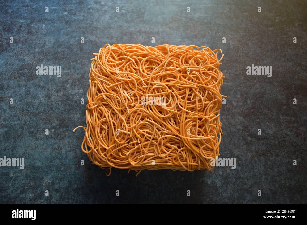 Raw whole dried orange color square noodles block Stock Photo - Alamy