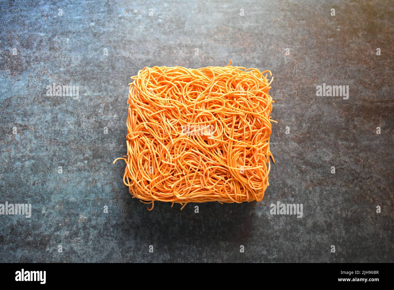 Raw whole dried orange color square noodles block Stock Photo - Alamy