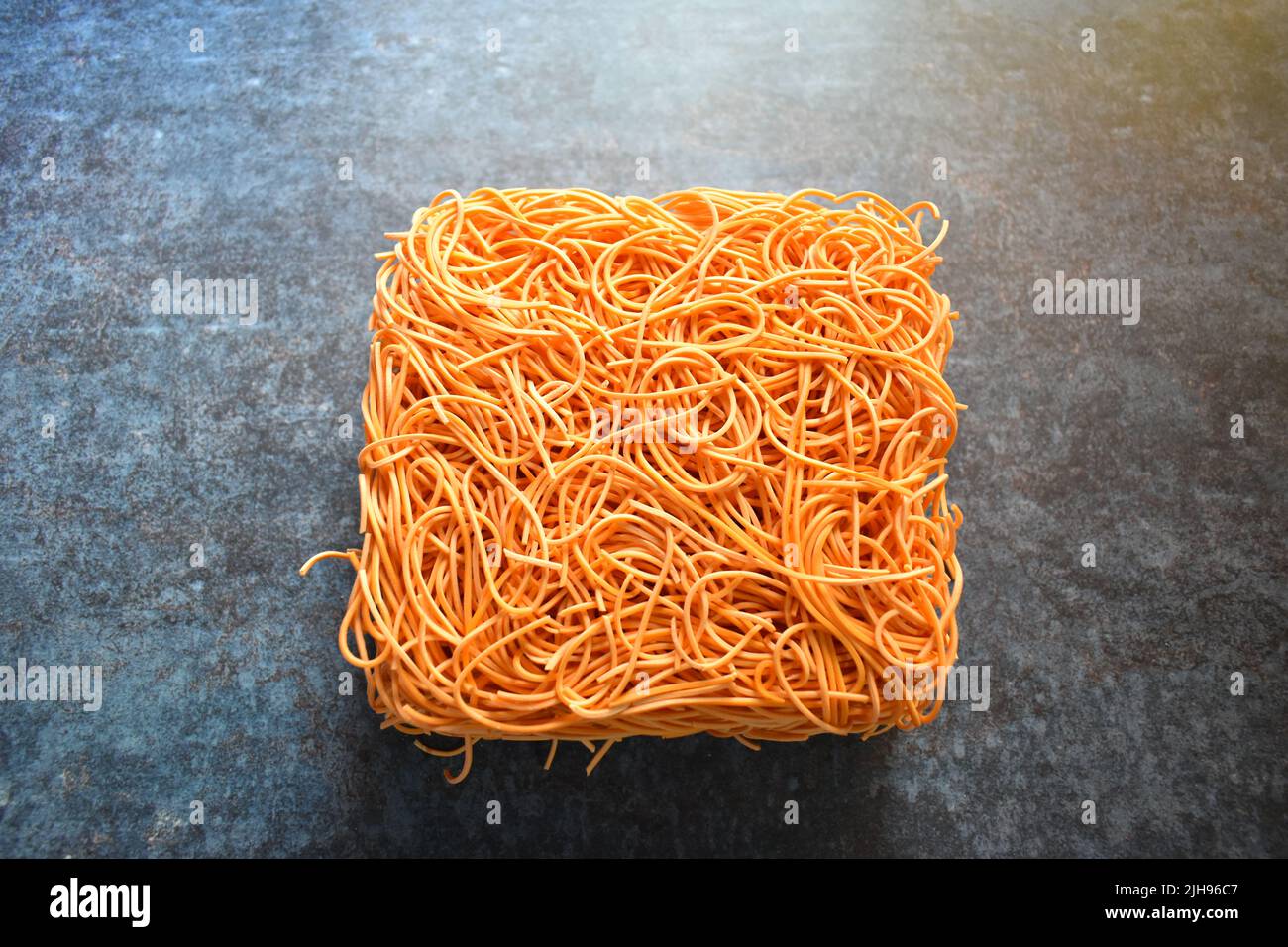 Raw whole dried orange color square noodles block Stock Photo - Alamy