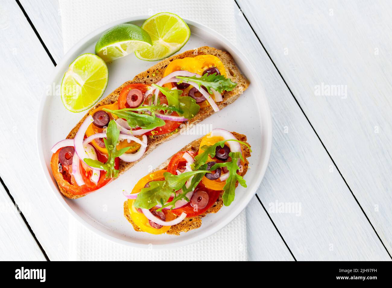 Vegetarian toasts and lime on a white plate. Bruschetta with tomatoes ...