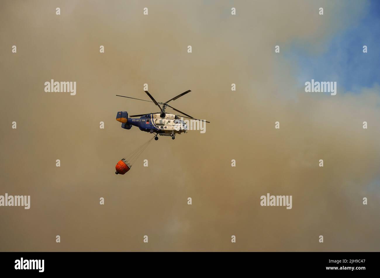 Heavy helicopter of INFOCA carrying a water bucket to drop on a ...