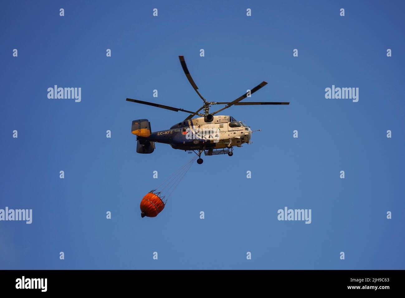 Heavy helicopter of INFOCA carrying a water bucket to drop on a ...