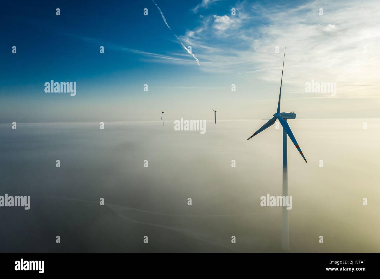 Misty sunrise and wind turbine with sun rays, Poland Stock Photo - Alamy