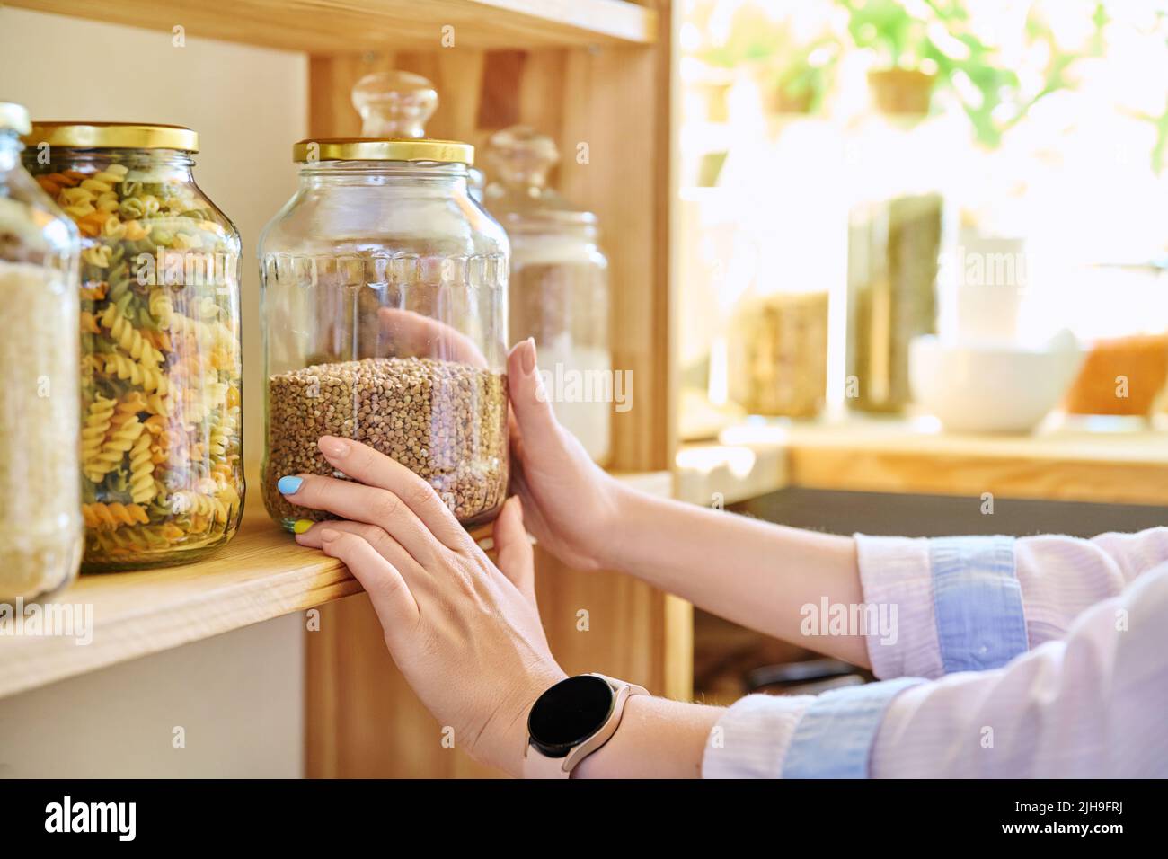 Storage of food in the kitchen in pantry, woman's hands with jar of ...