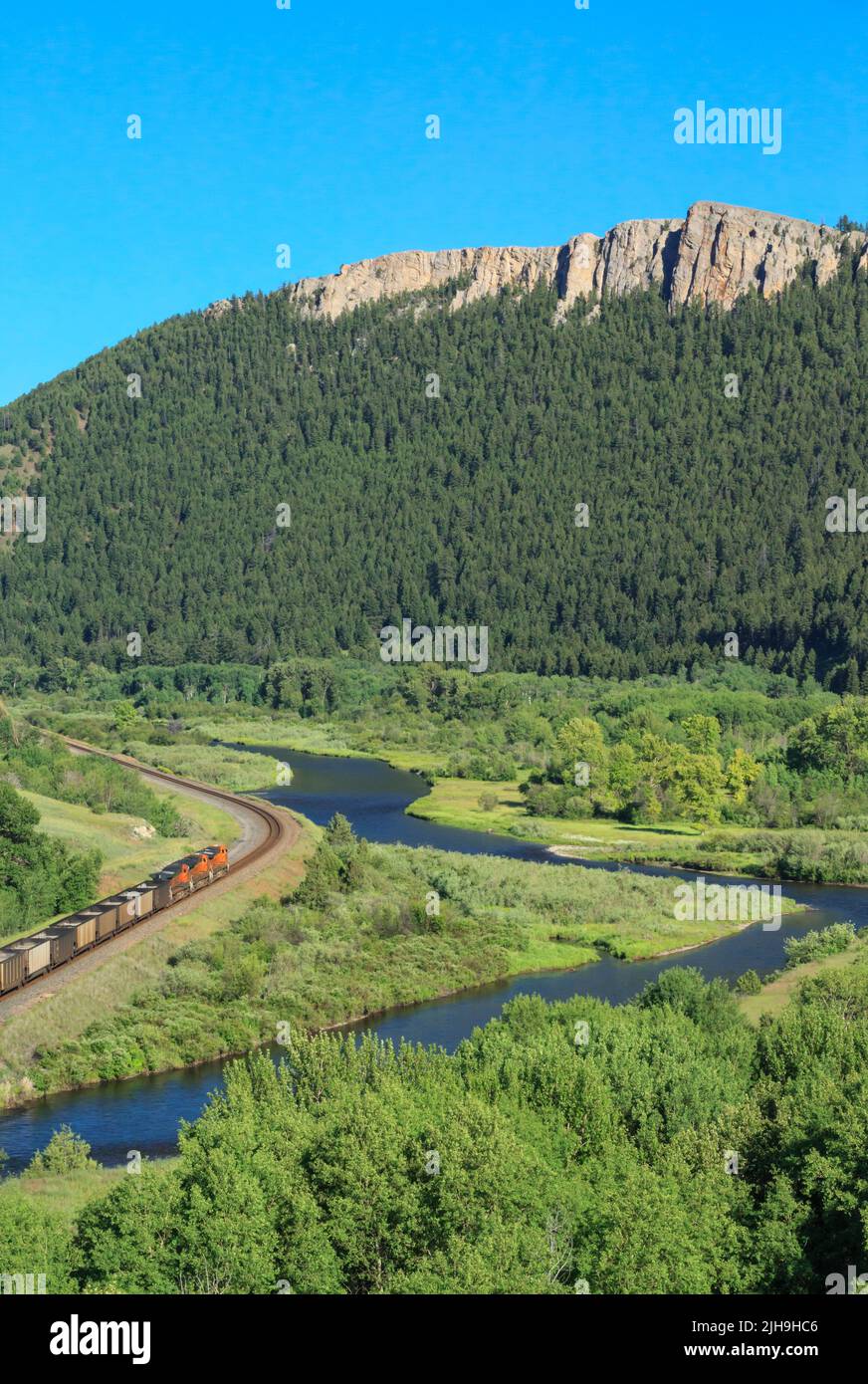 train on railroad tracks below high cliffs along the clark fork river ...
