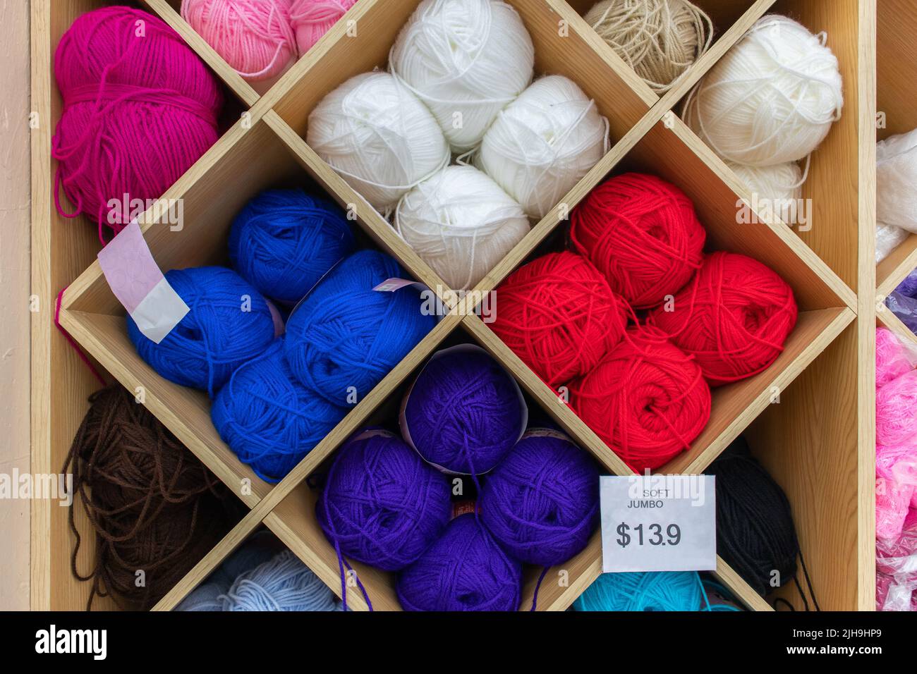 stack of colorful worsted wool yarn batch in square spaces of a shelf ...