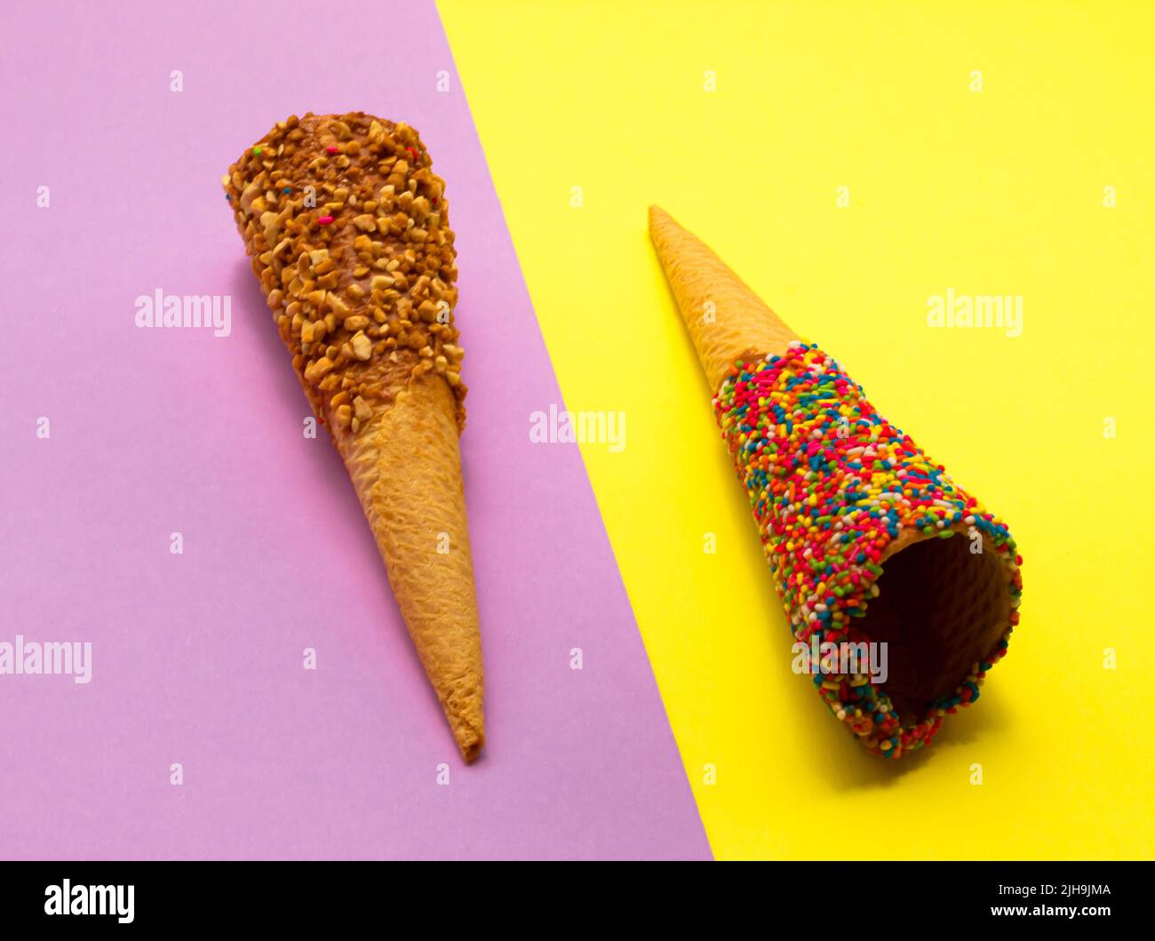Colorful ice cream waffle cones with sprinkles and hazelnut on pastel ...