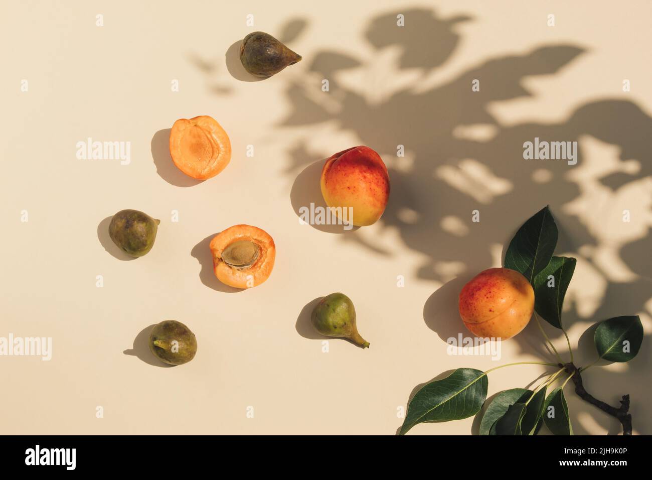 Summer scene with fresh apricot fruit, figs, leaves and tree shadow on ...