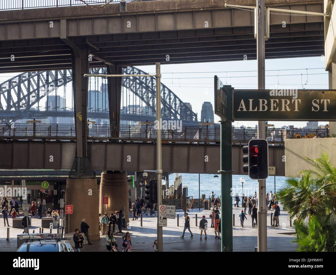 Tourists mill around Circular Quay with the Sydney Harbour Bridge in ...