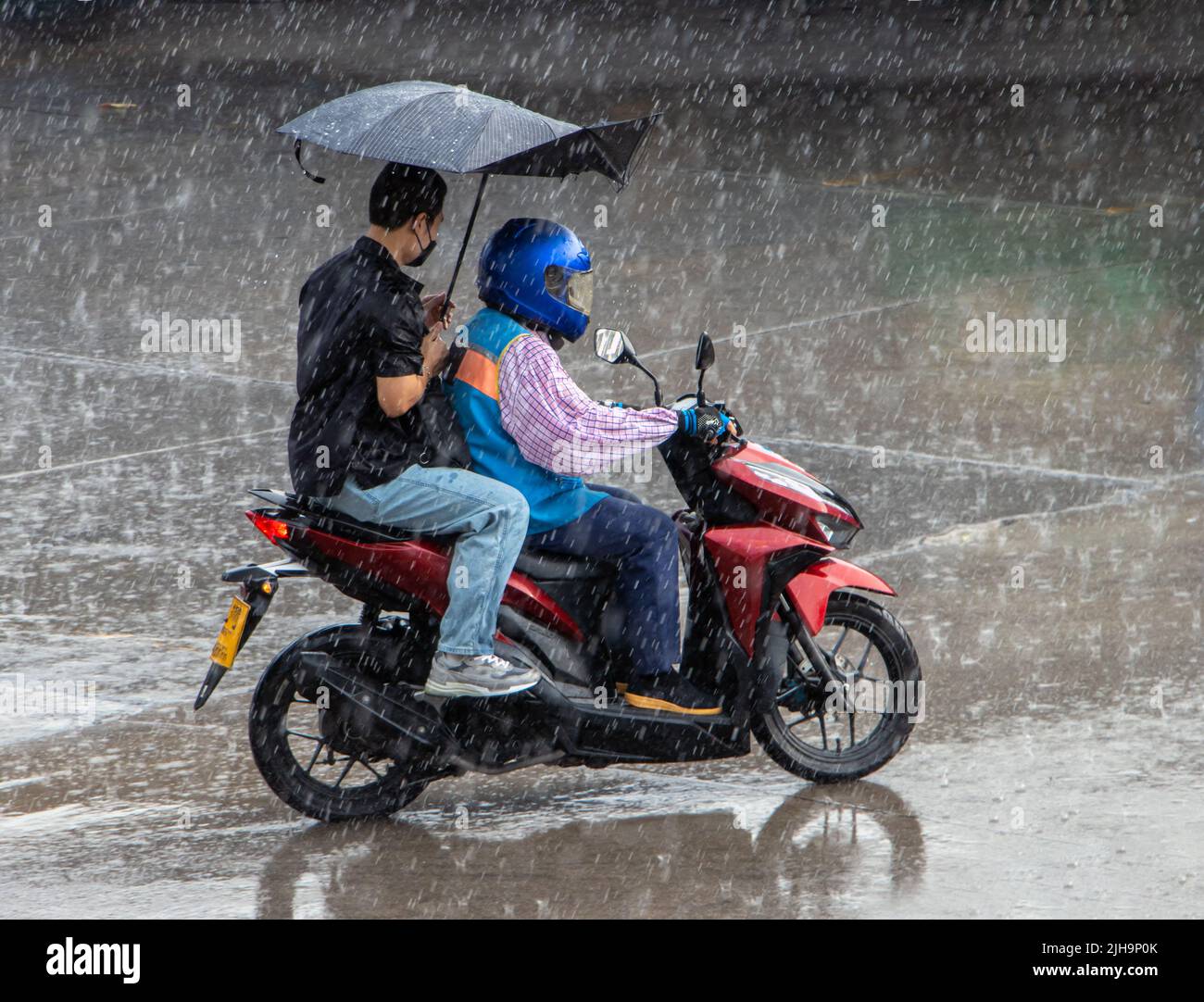 A motorcycle taxi driver with passenger rides in a heavy rain Stock ...