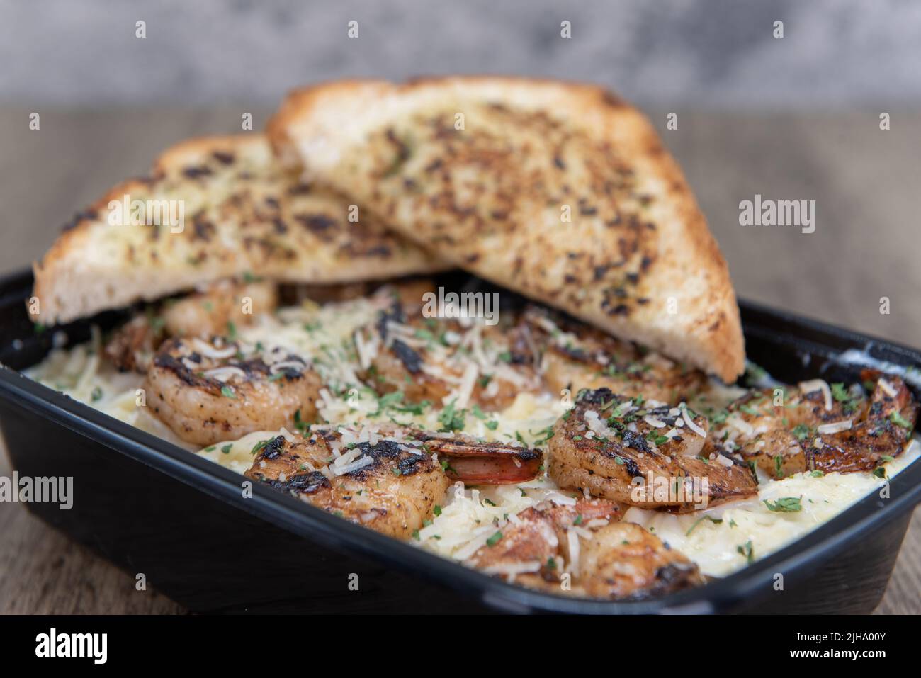 Cheesy bowl of shrimp alfredo served in a take out container with two ...