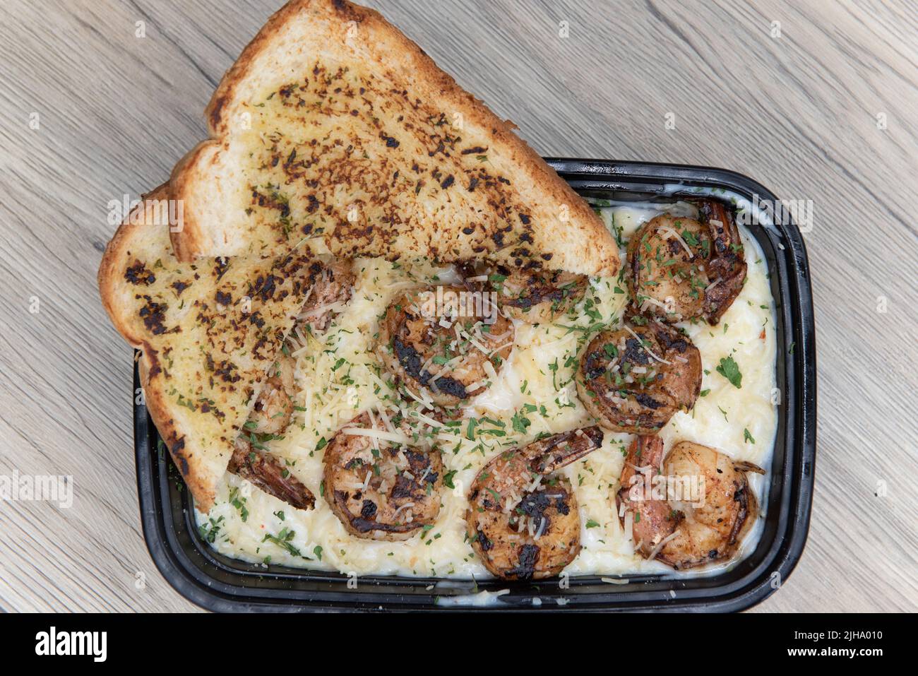 Overhead view of cheesy bowl of shrimp alfredo served in a take out ...